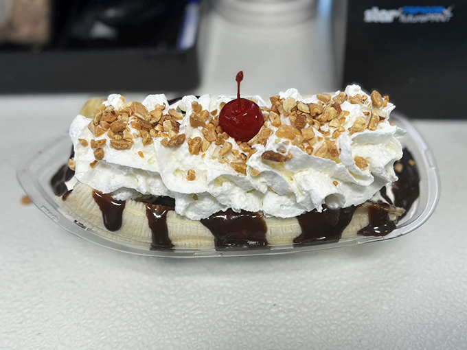 Behold the banana split in its natural habitat – a symphony of textures where warm chocolate sauce cascades over cool cream and fruit.