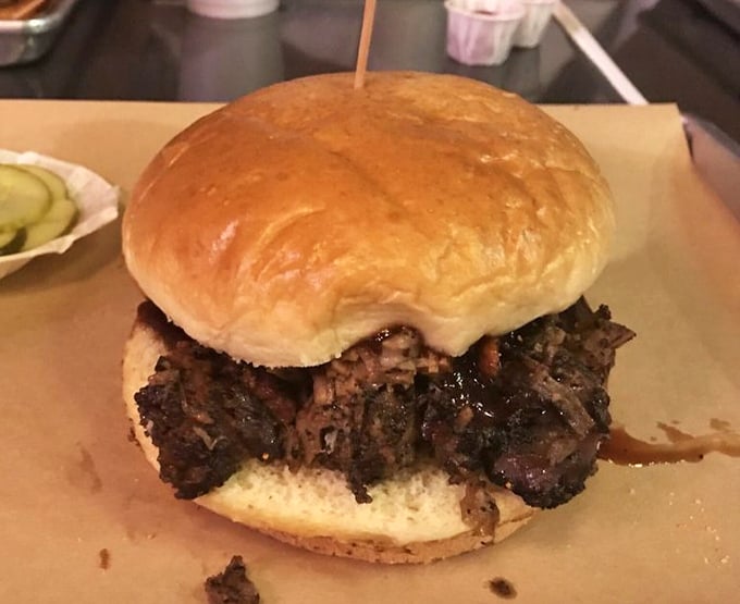 This isn't just a sandwich; it's an architectural marvel of smoke-kissed brisket that requires both hands, several napkins, and absolutely no shame.