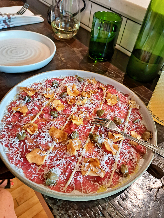 The star of the show&mdash;beef carpaccio swimming in golden olive oil with hazelnuts scattered like treasure. Proof that sometimes the best cooking involves no cooking at all.