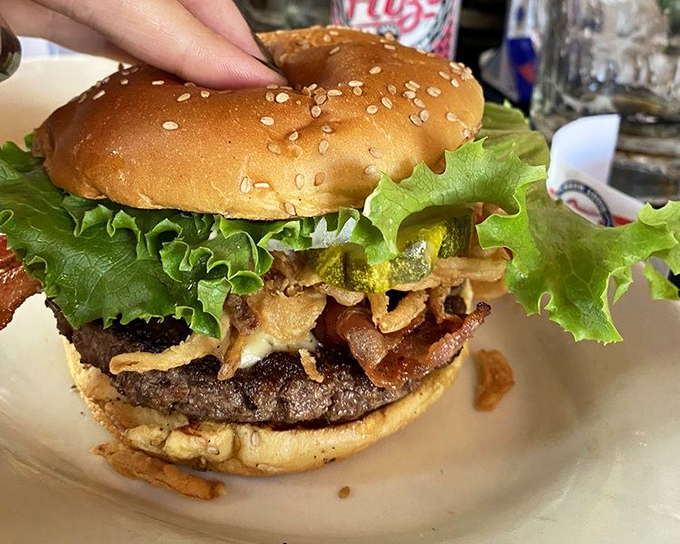 A burger that demands a jaw unhinging like a python&mdash;stacked with crispy onions, bacon, and fresh lettuce on a perfectly toasted sesame bun.
