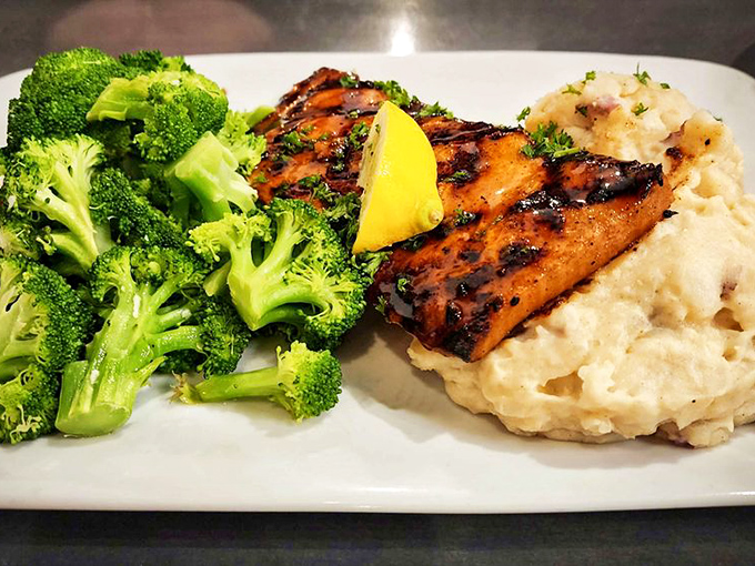Bourbon Street Salmon with its perfect char marks, nestled beside creamy mashed potatoes and vibrant broccoli—a trio that performs in perfect harmony.