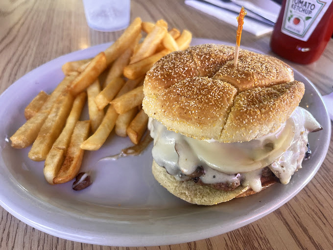 The cheeseburger arrives like a juicy monument to simplicity, melted cheese cascading down sides that have launched a thousand napkin grabs.