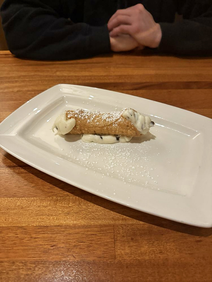 This cannoli isn't just dessert—it's edible architecture. Crisp shell, creamy filling, and a dusting of powdered sugar that would make a Sicilian weep.