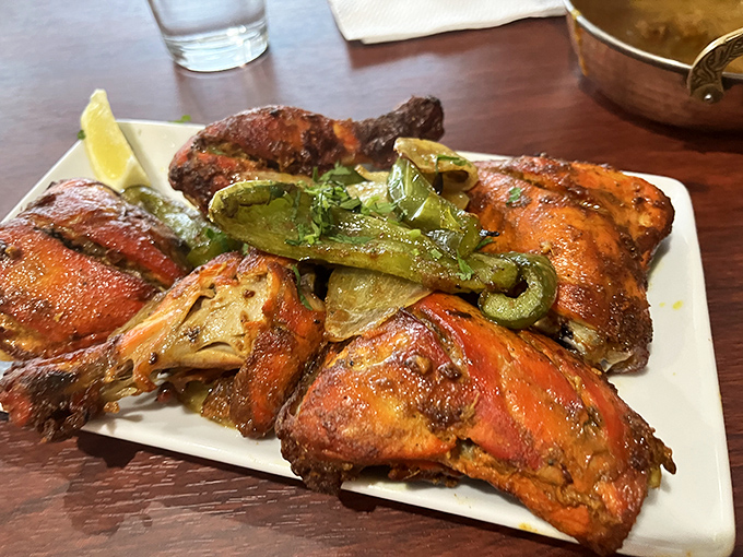 Tandoori chicken that's traveled through fire to reach your plate, sporting a sunset-colored spice crust and charred edges that whisper, "Worth every mile."