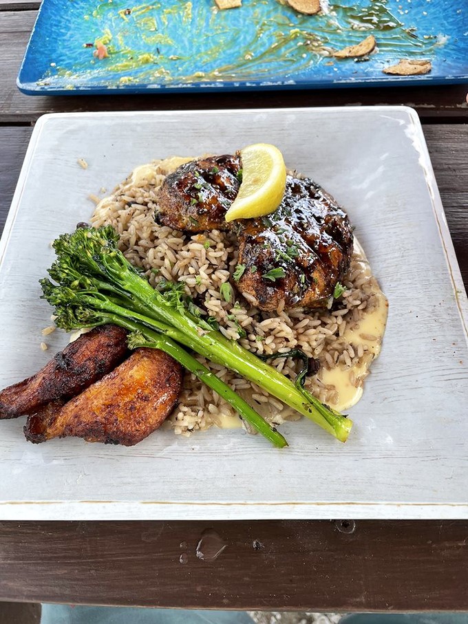Not just chicken—a masterclass in flavor layering. That Caribbean rice and perfectly charred broccolini might make you forget you're at a seafood joint.