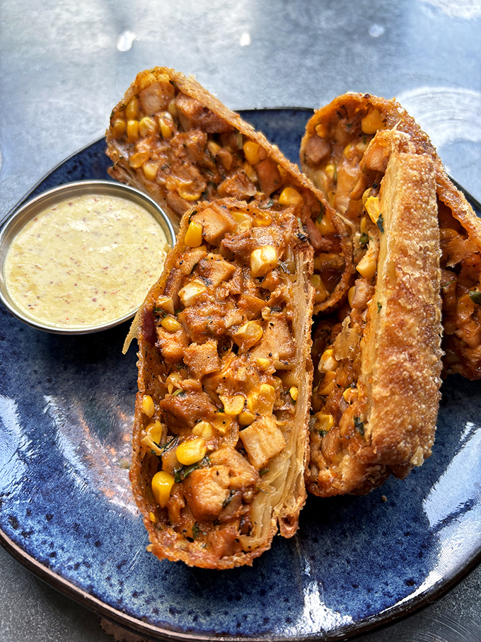 These aren't just egg rolls &ndash; they're crispy treasure chests filled with chicken and corn, served with a dipping sauce that'll make you consider drinking it straight.