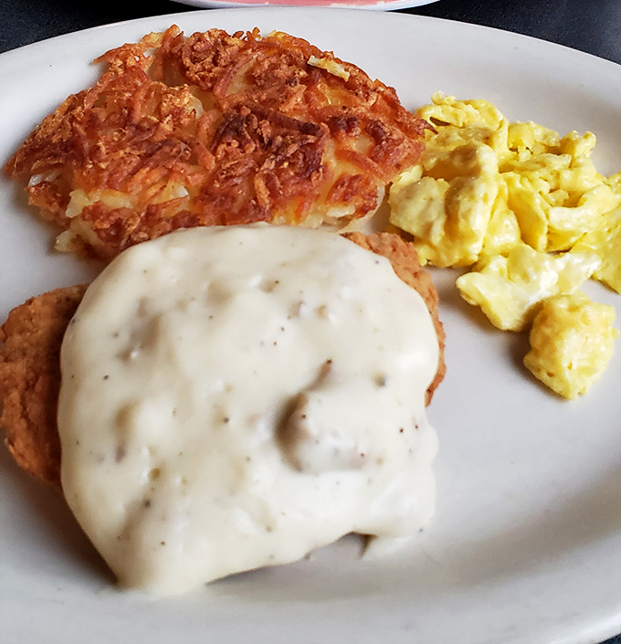 The holy trinity of comfort food: golden-fried chicken steak, creamy country gravy, and hash browns that could make a grown adult misty-eyed with nostalgia.