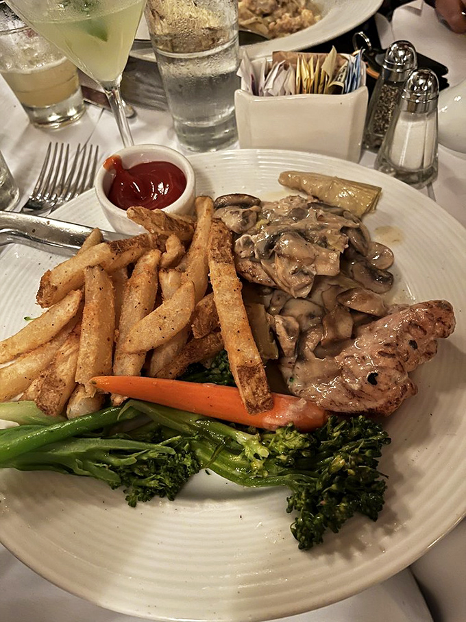 When mushroom sauce cascades over perfectly cooked chicken, paired with golden fries and fresh vegetables, Monday night suddenly feels like a celebration.