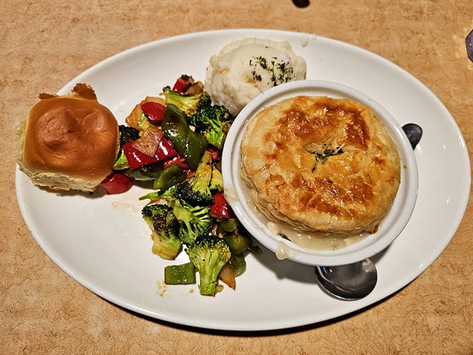 Not just any pot pie&mdash;this golden-crusted masterpiece shares the spotlight with colorful vegetables and a fresh roll, creating the ultimate comfort food ensemble.