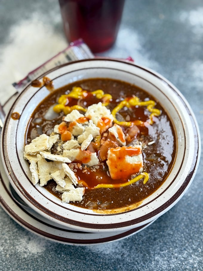 Bowl of chili so rich it could apply for its own tax bracket. Those crackers aren't garnish &ndash; they're life rafts in a delicious sea.