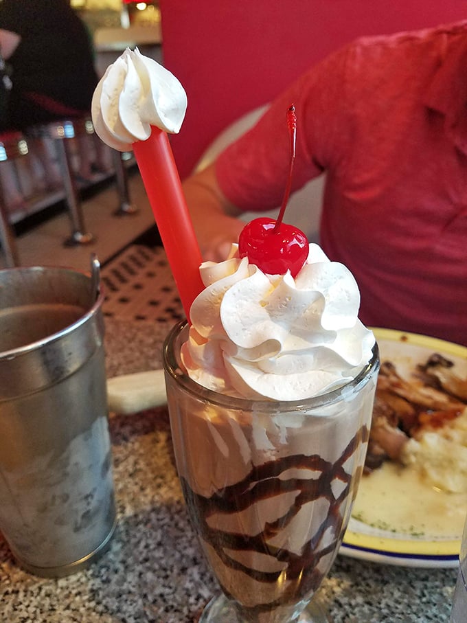 The chocolate malt arrives with whipped cream mountains and that signature metal mixing cup on the side &ndash; because one glass of heaven is never enough.