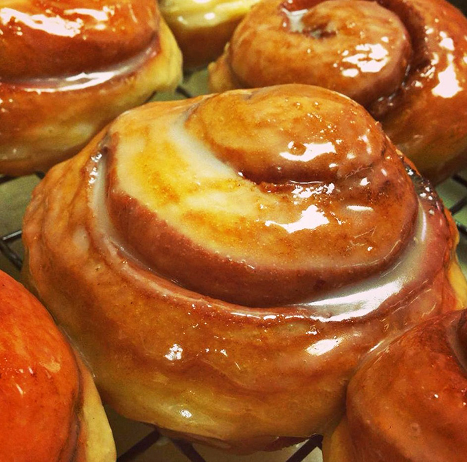 Cinnamon rolls glistening with glaze that captures the morning light like nature's own sugar-coated stained glass windows.