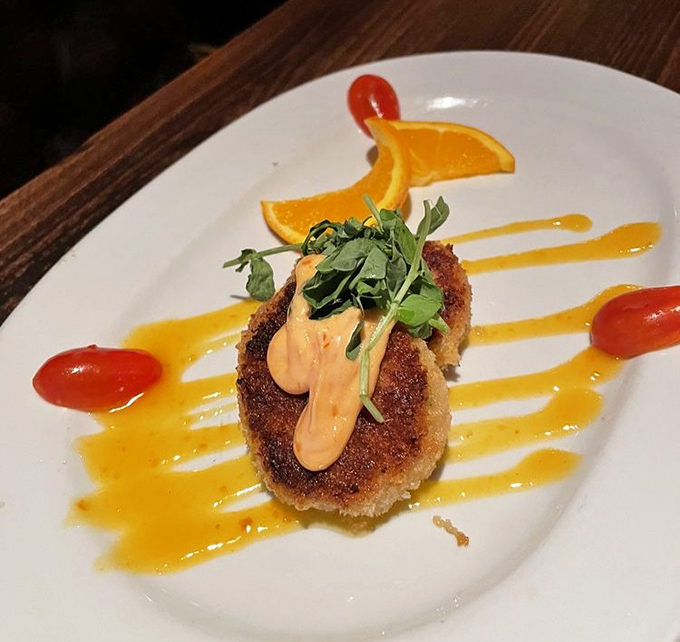 The legendary crab cake arrives like edible art&mdash;golden-brown perfection adorned with microgreens and a sunset-colored sauce that makes you wonder why you'd ever order anything else.