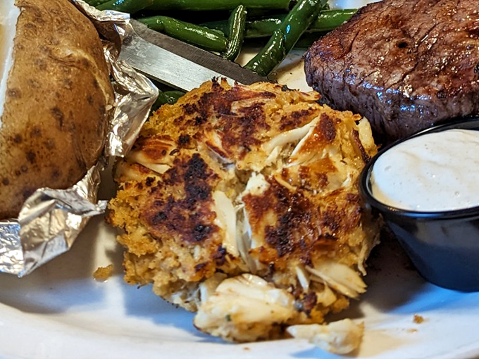 Crab cake perfection meets baked potato comfort. That golden-brown crust promises what lies beneath—sweet crabmeat held together by little more than hope and skill.