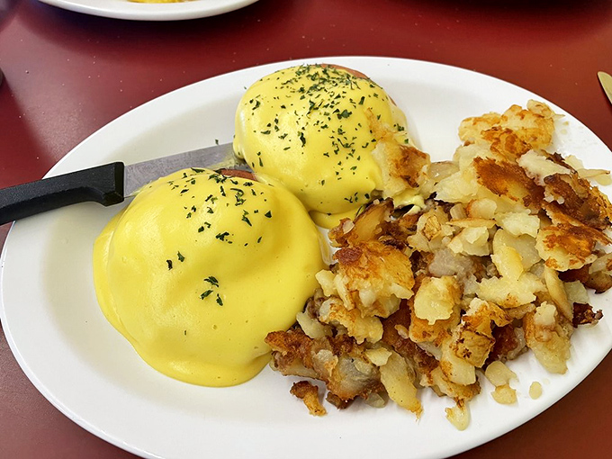 Eggs Benedict done diner-style: golden hollandaise cascading over perfectly poached eggs, with home fries crisped to that magical point between tender and crunchy.