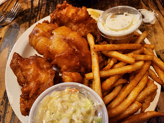 Golden-battered fish that shatters like delicate glass when your fork touches it. This isn't just fish and chips &ndash; it's edible sunshine on a plate.
