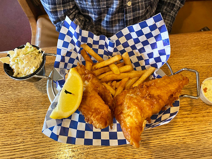 Fish and chips served in a blue-checkered paper boat&mdash;because even seafood deserves a cute outfit before meeting its delicious demise.