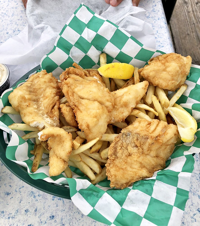 Golden-battered fish and chips that shatter with each bite, served on checkered paper—proof that simplicity, when done right, is culinary genius.