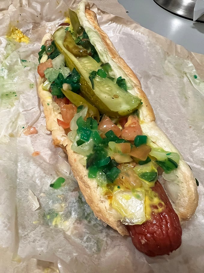 A foot-long masterpiece dressed to impress with pickles, tomatoes, and enough toppings to require structural engineering skills.