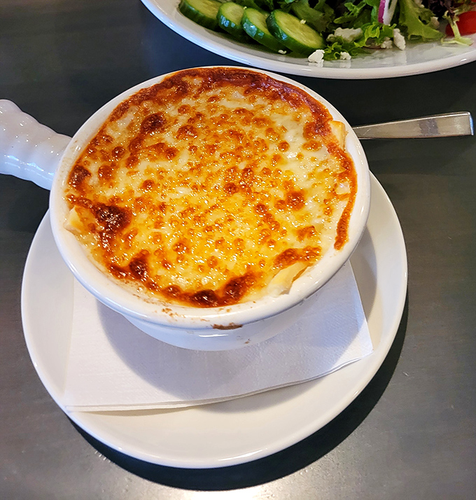Bubbling cheese forms a golden canopy over this French onion soup, waiting to be broken like cr&egrave;me br&ucirc;l&eacute;e's savory cousin.