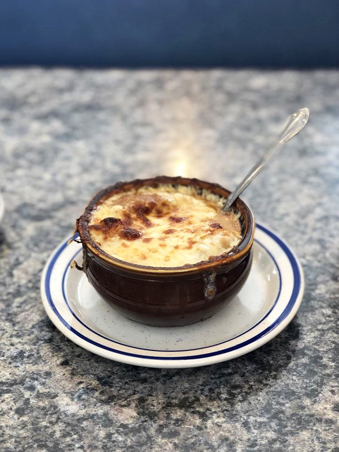 The French onion soup arrives like a warm hug in a crock—bubbling cheese stretched across the top like nature's perfect comfort food forcefield.