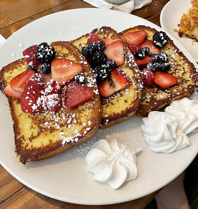 French toast that's lived its best life &ndash; soaked overnight, caramelized to perfection, and adorned with berries that pop against the powdered sugar snow.