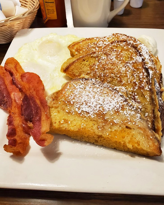 French toast that's achieved the impossible: perfectly crisp edges with a custardy center, dusted with powdered sugar and served with bacon for balance.