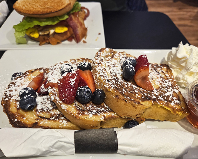 French toast that makes you question all other breakfast decisions &ndash; golden challah adorned with fresh berries and a snowfall of powdered sugar.