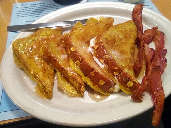 French toast that's achieved the golden ratio of crispy exterior and custardy interior. Those strips of bacon aren't just a side&mdash;they're essential supporting actors in this breakfast drama.