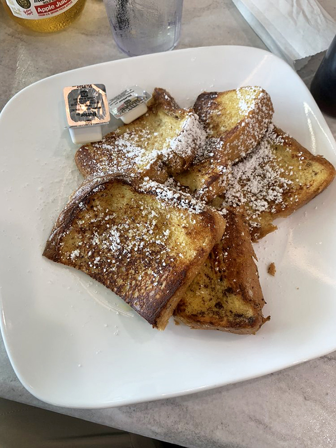 The French toast that launched a thousand return visits&mdash;golden, crispy edges giving way to custardy centers under a snowy dusting of powdered sugar.