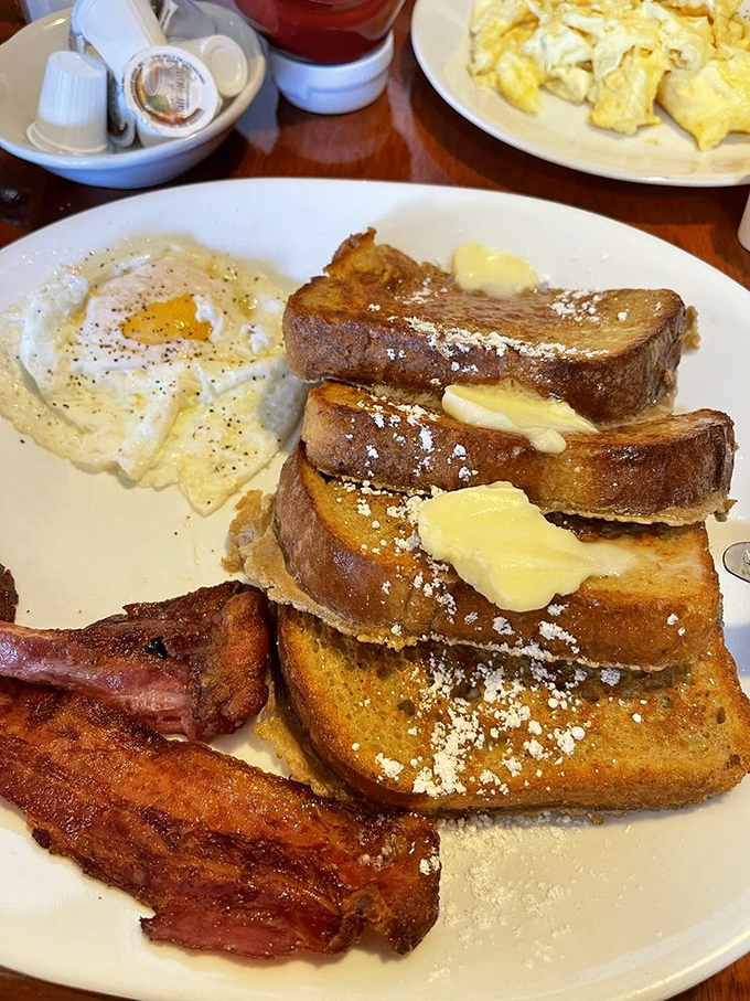 French toast stacked higher than your weekend expectations. Those butter pats aren't melting&mdash;they're surrendering to the inevitable deliciousness.