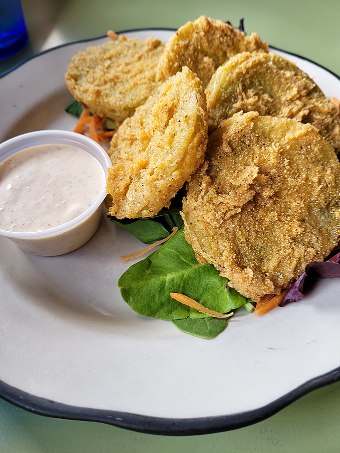 Golden-fried green tomatoes that crunch like autumn leaves, nestled on fresh greens with a side of ranch that deserves its own fan club.