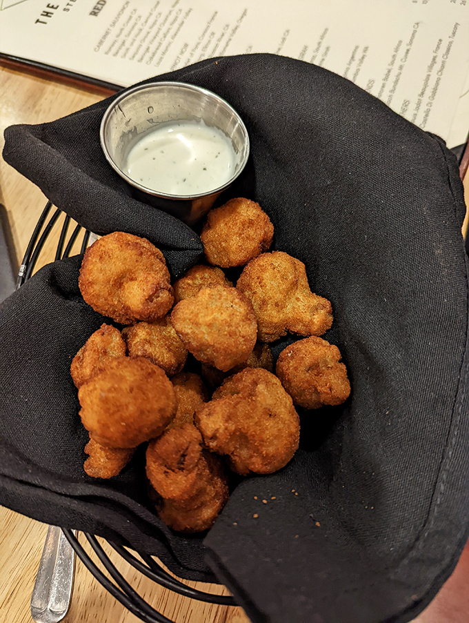 Golden-fried mushrooms nestled in their black napkin hammock. These crispy morsels are what vegetable dreams are made of when they grow up.