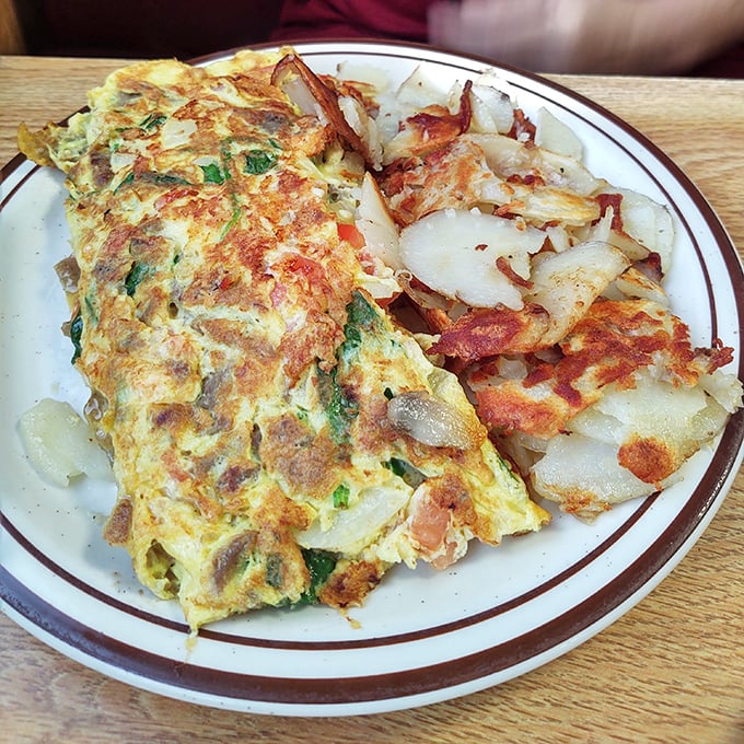 This isn't just an omelet&mdash;it's an architectural achievement. Perfectly folded eggs housing a treasure trove of fillings, with hash browns crisped to golden perfection.
