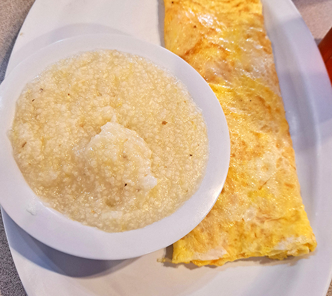 Creamy grits alongside a perfectly folded omelet. Southern comfort meets technical precision on a single plate.