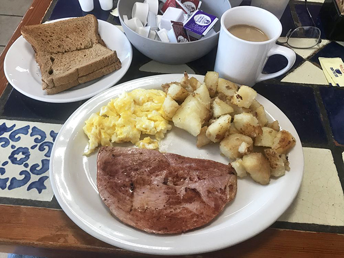 Breakfast of champions: ham steak with that perfect caramelized edge, fluffy scrambled eggs, and home fries that dance between crispy and tender.