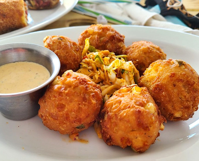 These hush puppies aren't telling tales, but they're speaking volumes about perfect frying technique. Crispy outside, tender inside, with a dipping sauce that demands attention.