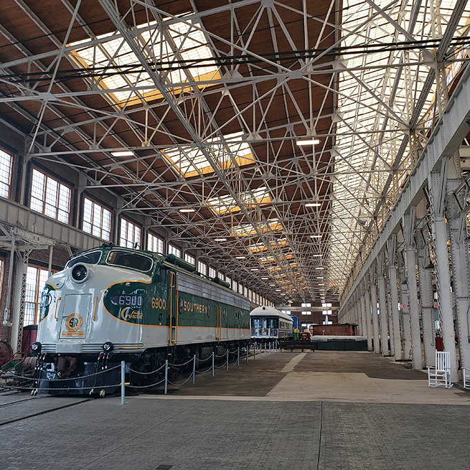 Southern Railway's streamlined diesel locomotive 6900 rests in the cavernous Back Shop, its sleek green and gold livery still commanding attention after decades of service.