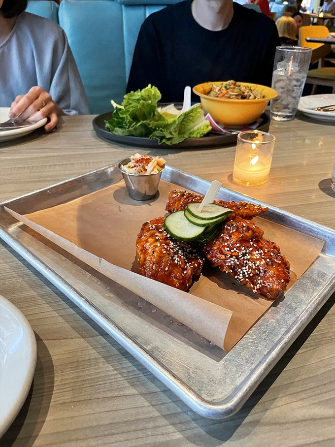 The Korean Fried Chicken arrives like a glazed masterpiece—crispy, sticky, sweet, and spicy—with cooling cucumber slices that provide the perfect counterpoint.