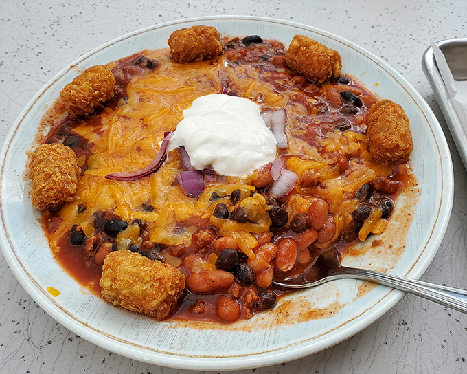 Comfort in a bowl: hearty chili crowned with melted cheddar, sour cream, and surrounded by golden tater tots. Winter blues don't stand a chance against this.