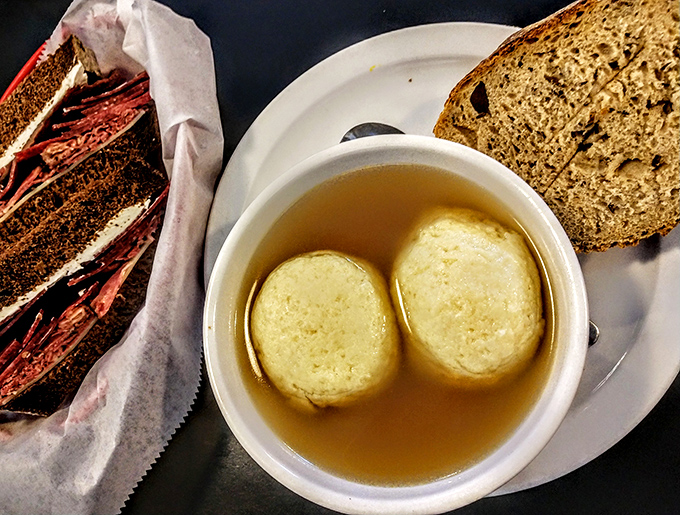 Matzo ball soup that would make any Jewish grandmother nod approvingly—golden broth cradling fluffy dumplings that float like delicious clouds in a savory sky.