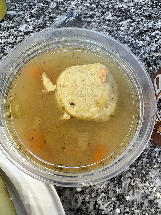 The matzo ball soup—a golden elixir cradling what can only be described as a cloud that somehow became deliciously solid.