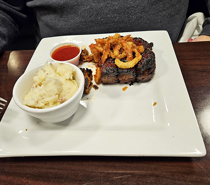 A steak that means business, accompanied by creamy mashed potatoes and crispy onion straws &ndash; the holy trinity of steakhouse satisfaction.