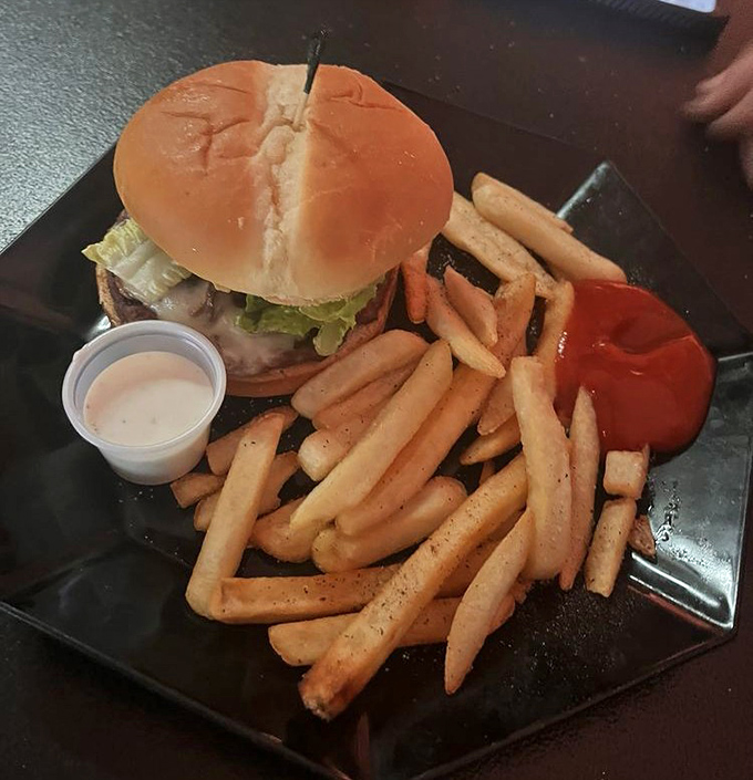 A burger that requires both hands and a strategy, paired with fries that could make a Frenchman reconsider his citizenship.