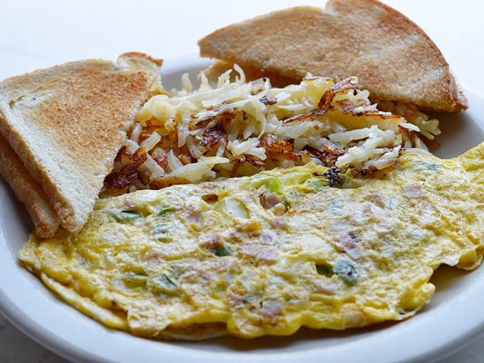 Breakfast perfection: a fluffy omelet studded with veggies alongside crispy hash browns and toast. Morning salvation on a plate. 
