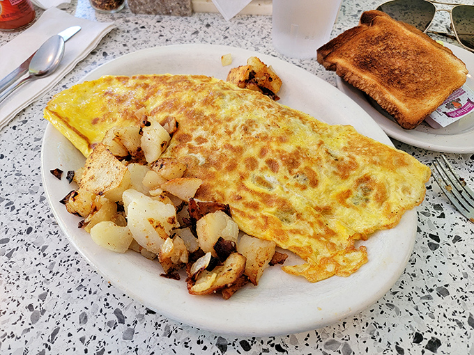An omelet so perfectly executed it deserves its own cooking show, accompanied by home fries that could make a potato farmer weep with pride.