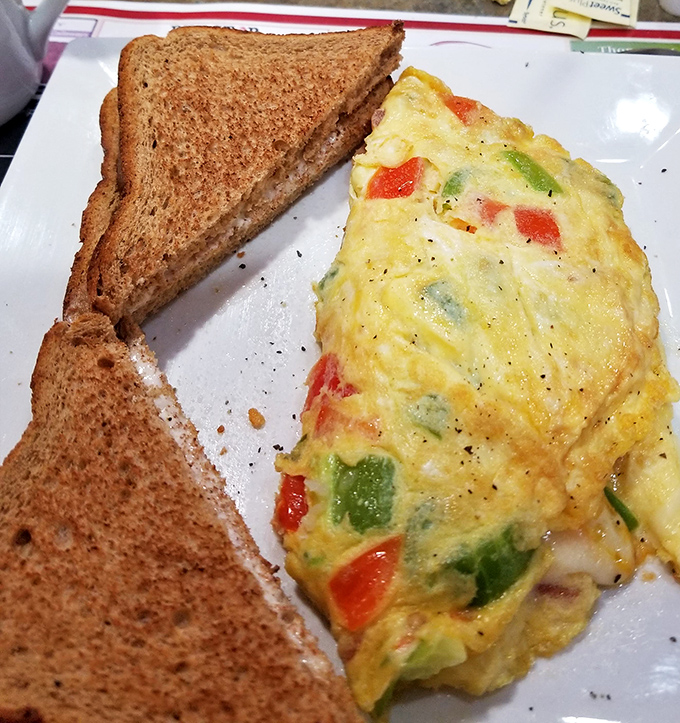 This isn't just an omelet; it's a vegetable-studded canvas of breakfast artistry that makes morning meetings worth enduring.