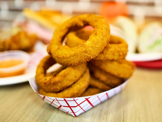 Golden onion rings stacked like delicious edible jewelry – crispy on the outside, tender within, and impossible to eat just one.
