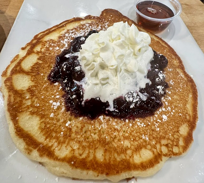 This pancake wears whipped cream and berry compote like a crown, proving breakfast can absolutely count as dessert.
