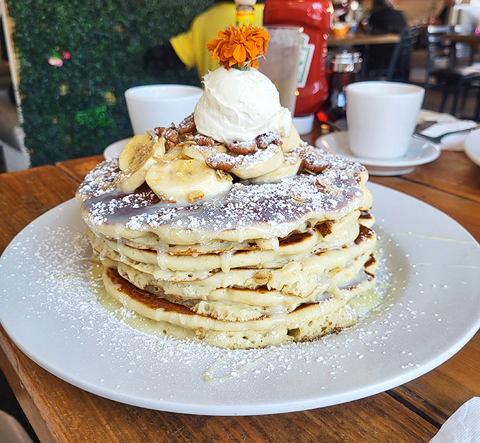 Not just pancakes, but a towering monument to morning indulgence, complete with fresh fruit and a dollop of whipped cream that defies gravity.